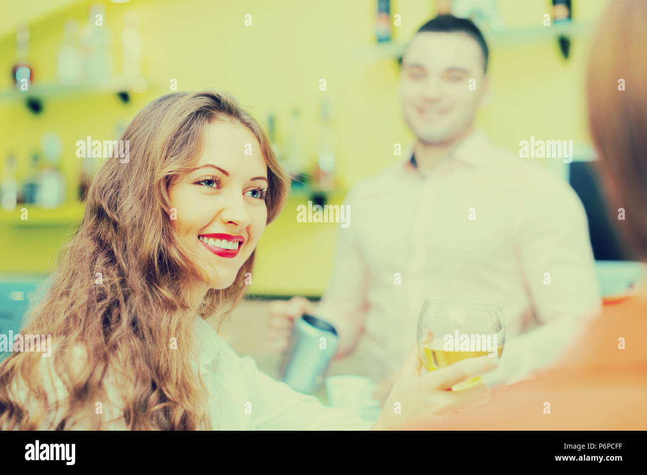 Two beautiful female friends flirting with a handsome barman Stock ...