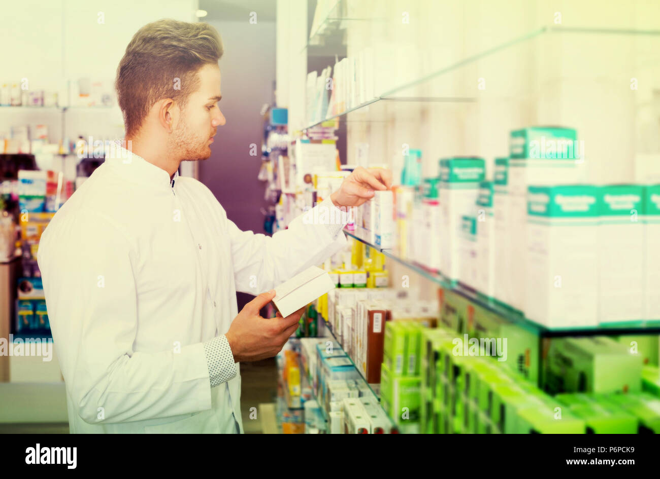 Adult man pharmacist wearing uniform and working in pharmaceutical shop ...