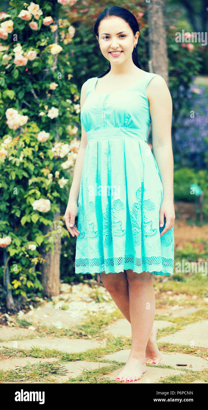 portrait of young happy germany female in dress near roses in a park ...