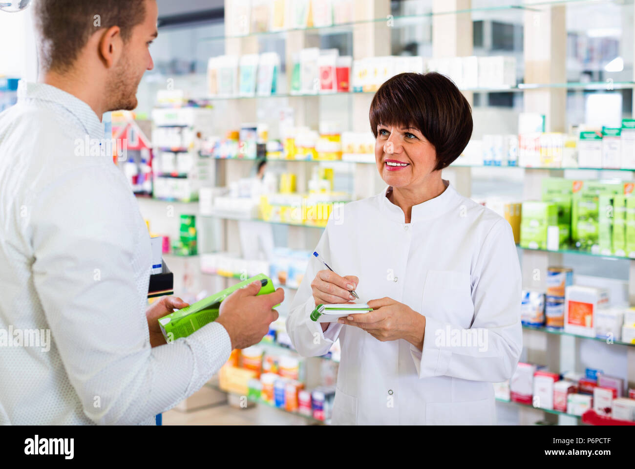 Smiling glad cheerful female pharmacist wearing uniform working in ...