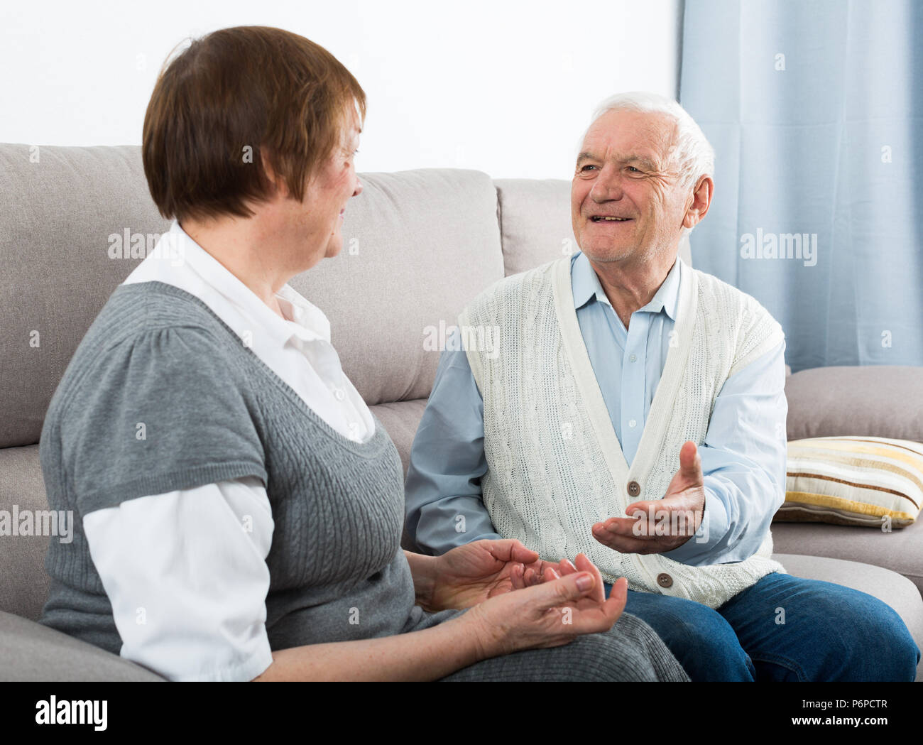 Elderly couple friendly talking sitting at home on sofa Stock Photo - Alamy