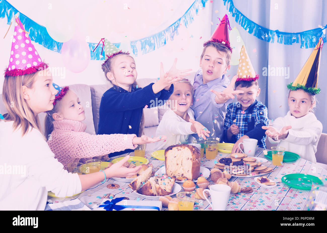Positive boys and girls happy to eat and drink at friend’s birthday ...