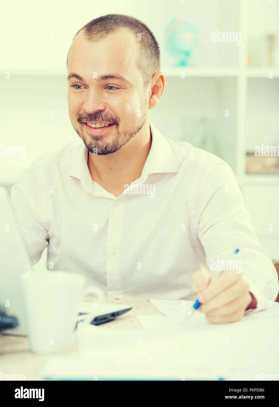 Positive young working man reading documents at his workplace Stock ...