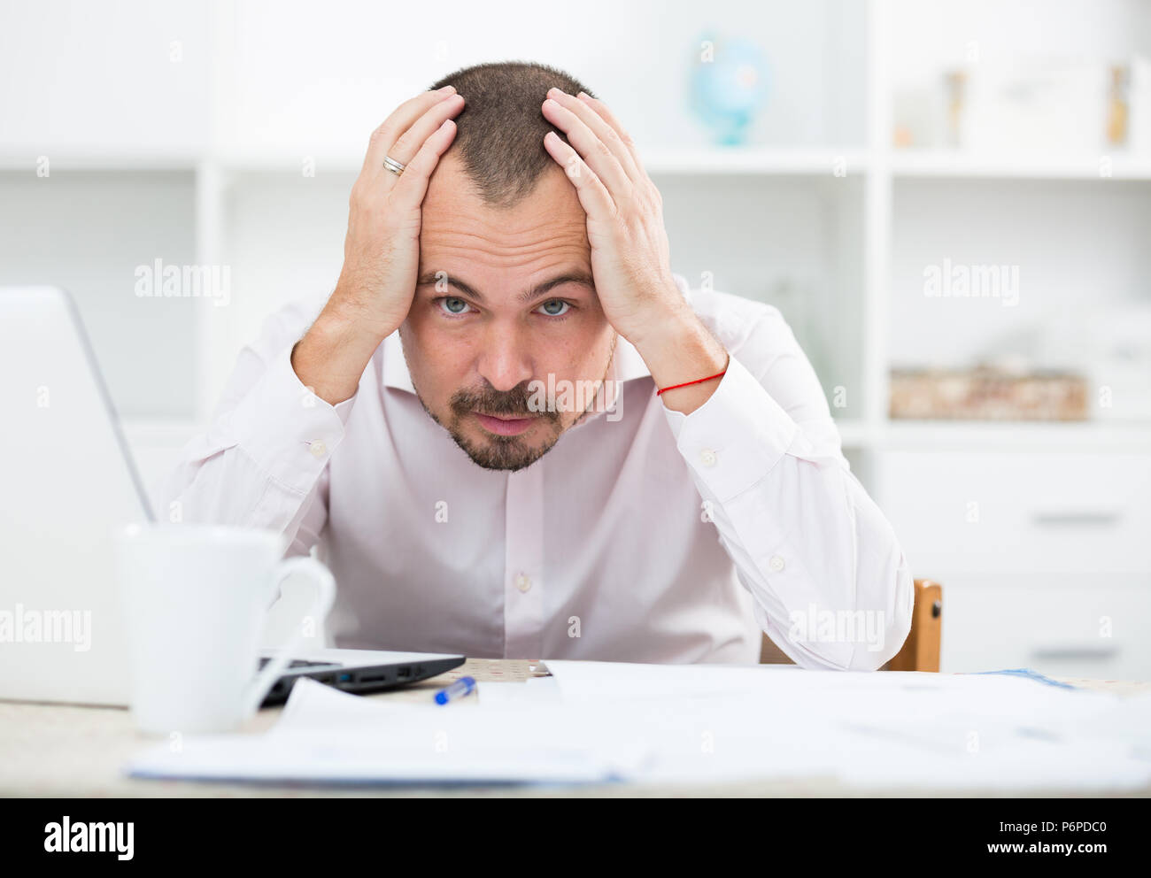 Disappointed worker at his office table feeling stressed, thinking and ...