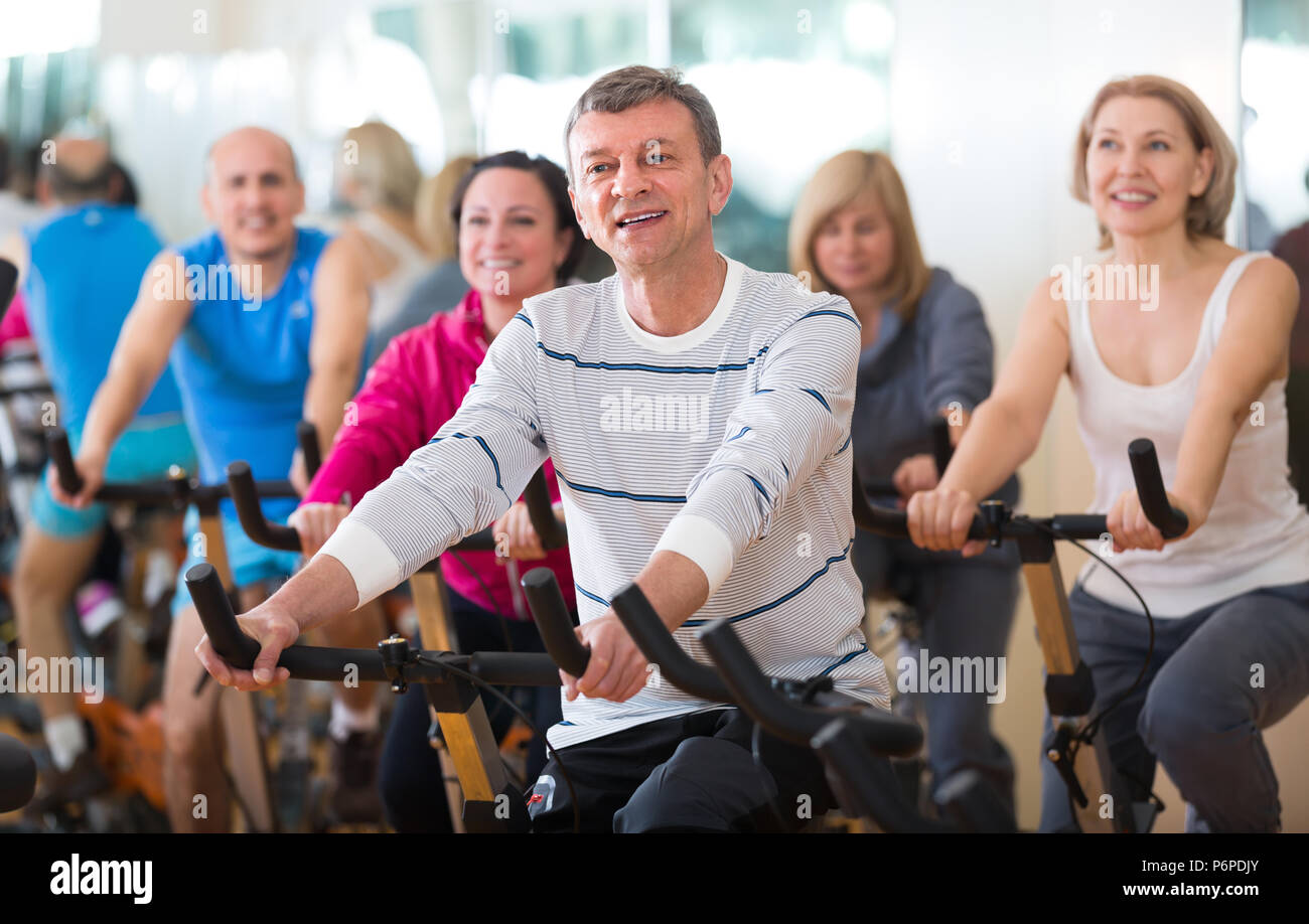 Positive smiling aged man on fitness cycle in fitness club Stock Photo ...