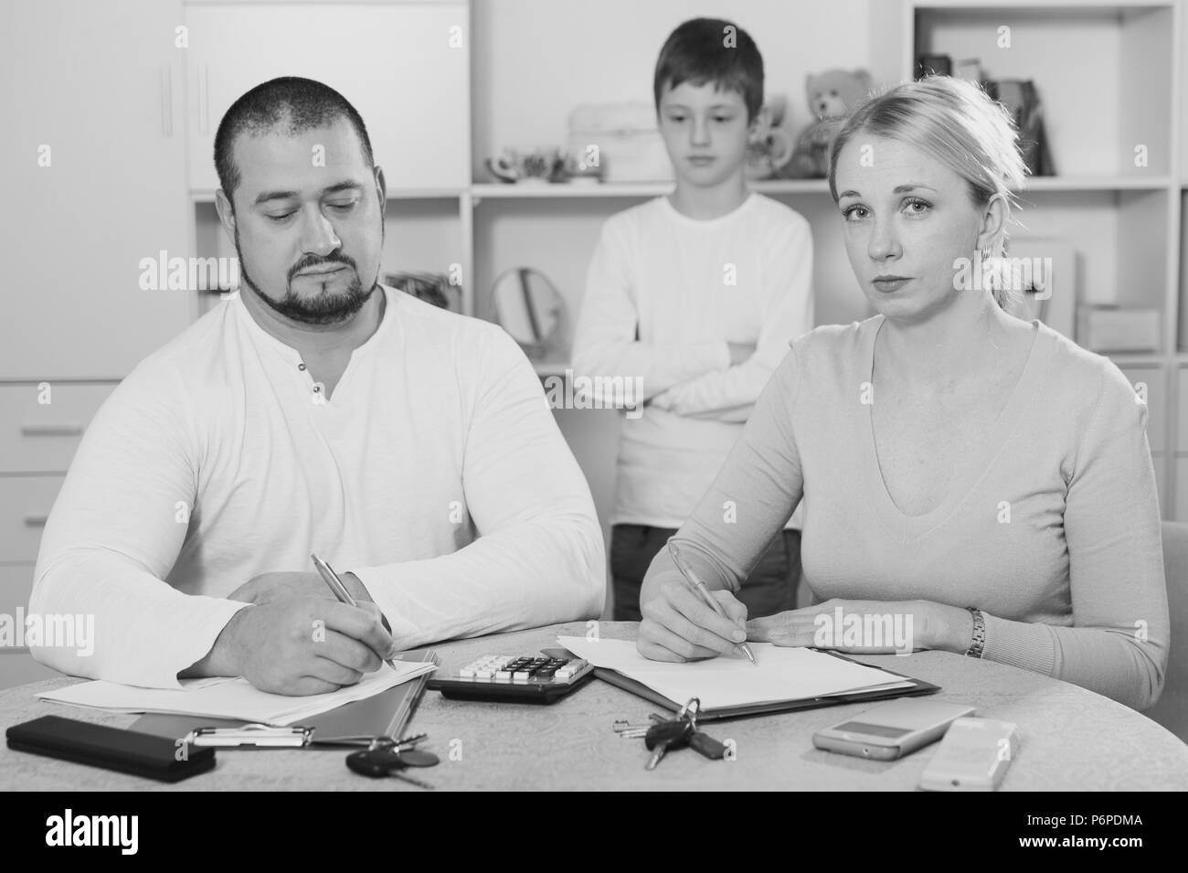 Serious young family working with papers at home on background with ...
