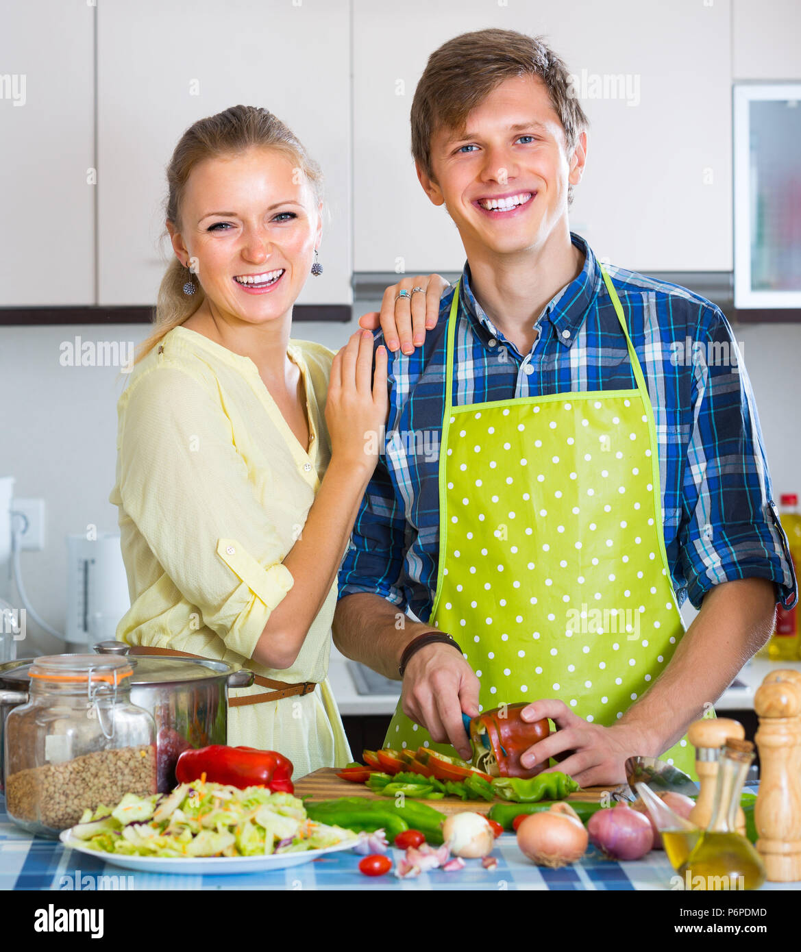 Cheerful young couple cooking vegetables in domestic kitchen Stock ...