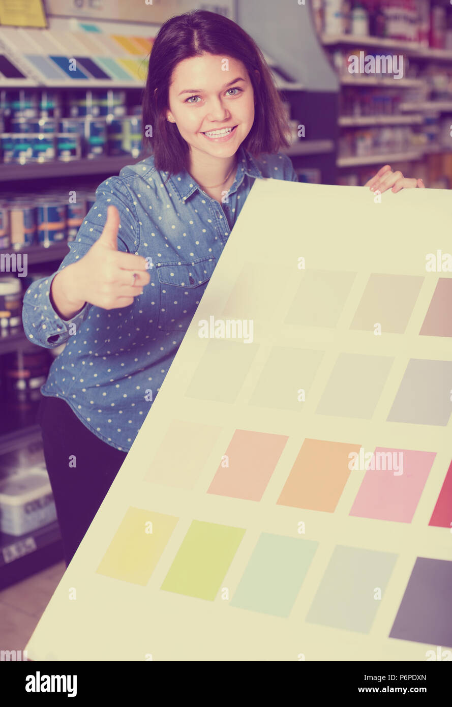 smiling female customer examining color scheme variants in paint ...