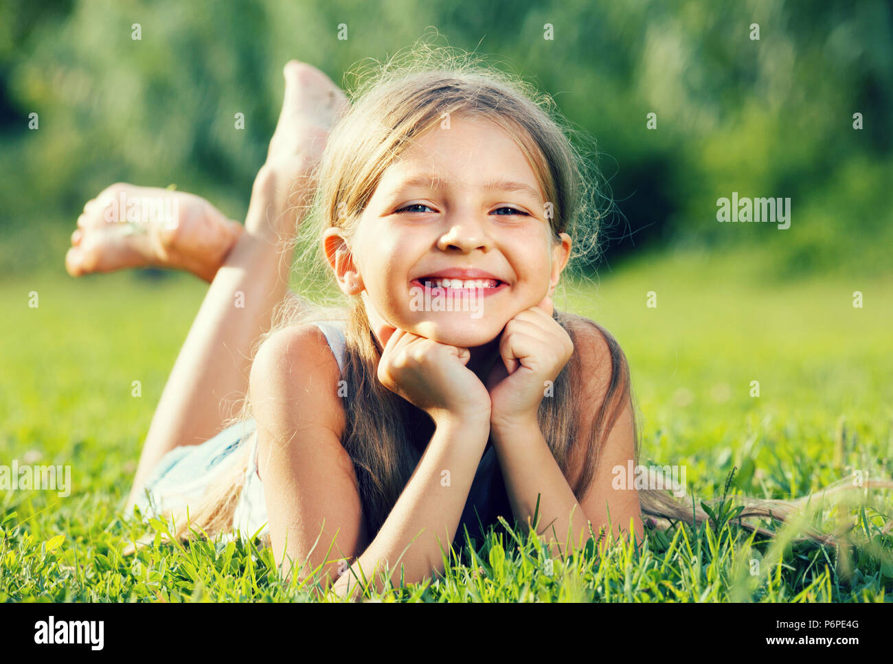 portrait of smiling girl in lying on grass in park and looking happy ...