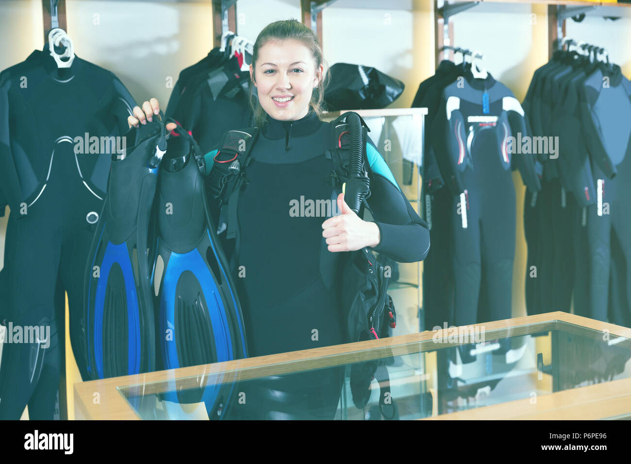 Female is standing in full set of modern diving equipment in the store ...