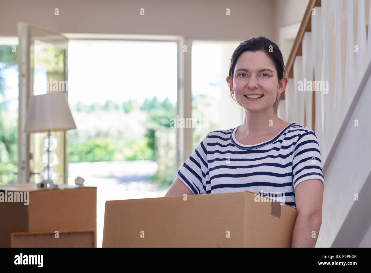 Portrait Of Woman Carrying Boxes Into New Home On Moving Day Stock ...