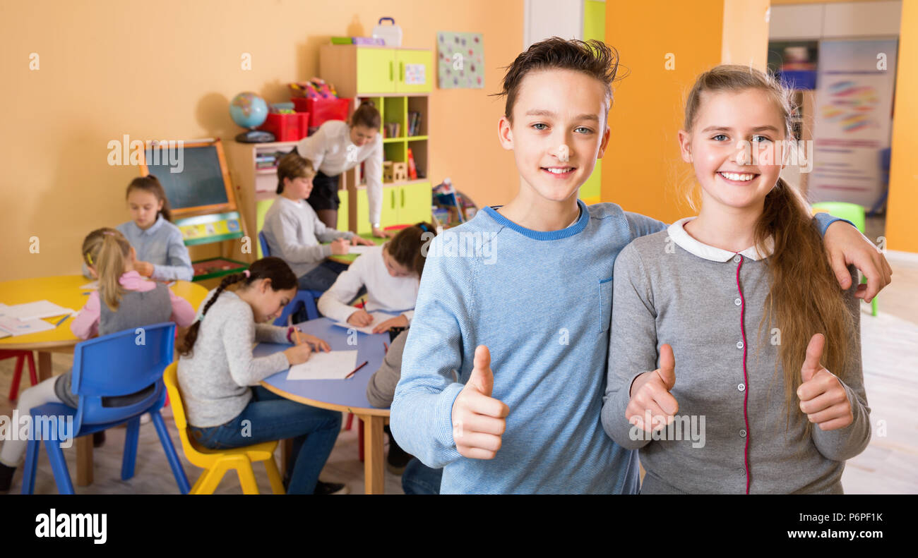 Two satisfied smiling positive children standing in schoolroom on ...
