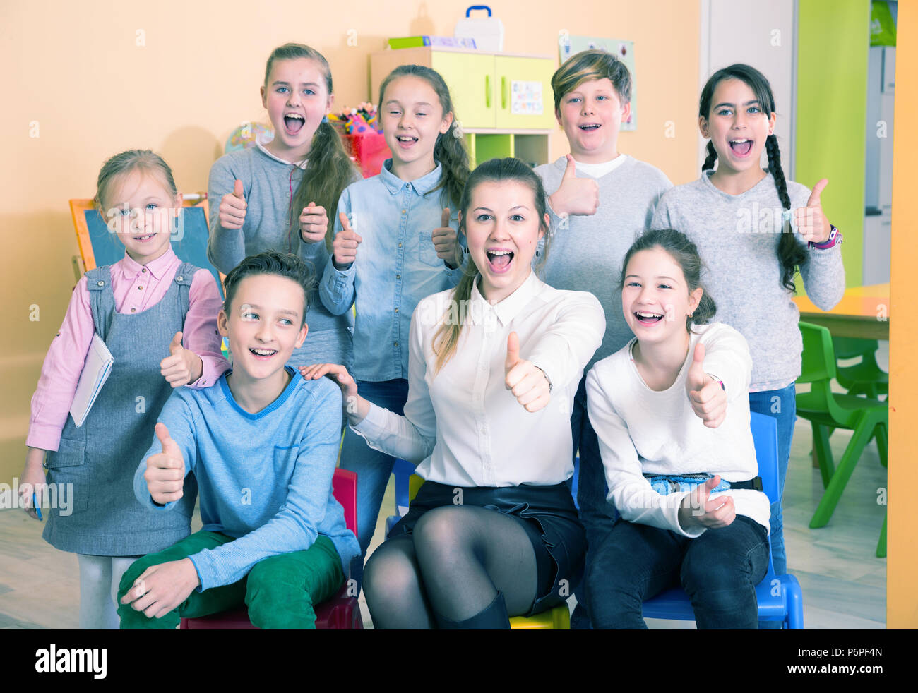 Cheerful group of pupils with female teacher posing together in ...