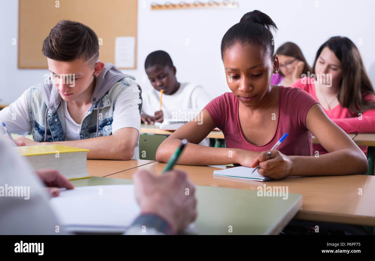 Group of multiethnic students making notes at the lesson in the ...