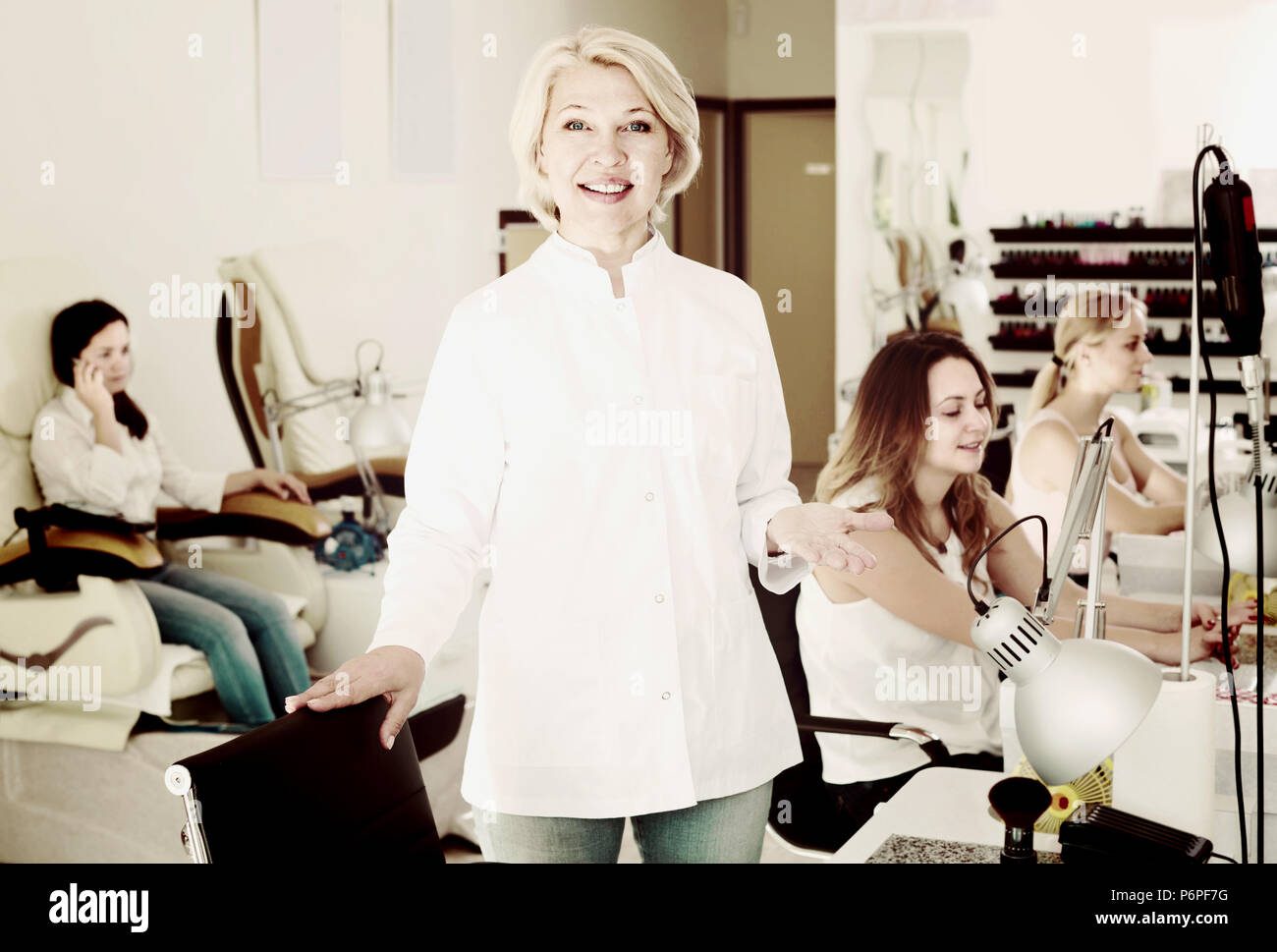 Smiling female manicurist showing her workplace in nail salon Stock ...