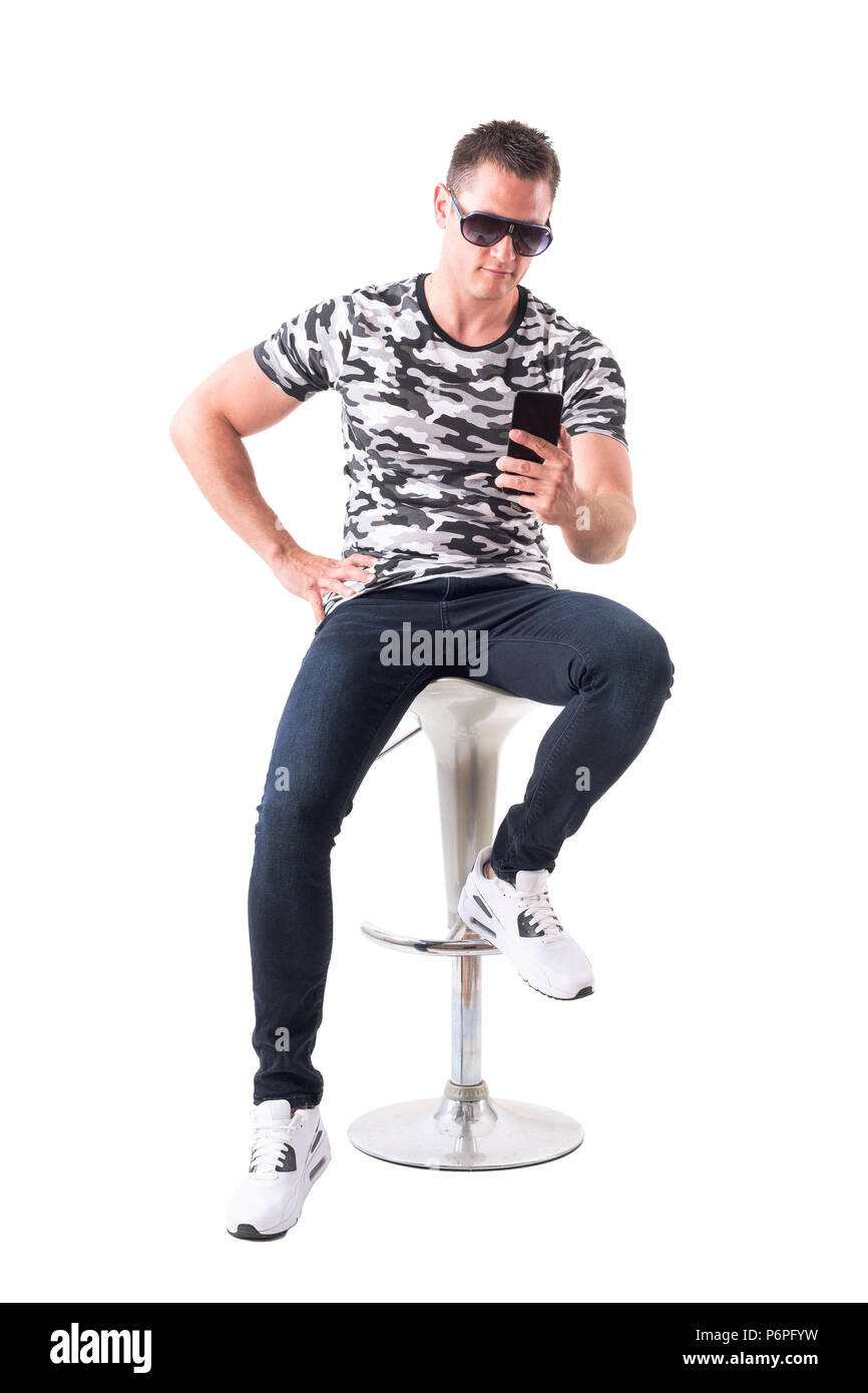 Young adult handsome man in camo t-shirt sitting on bar stool taking ...