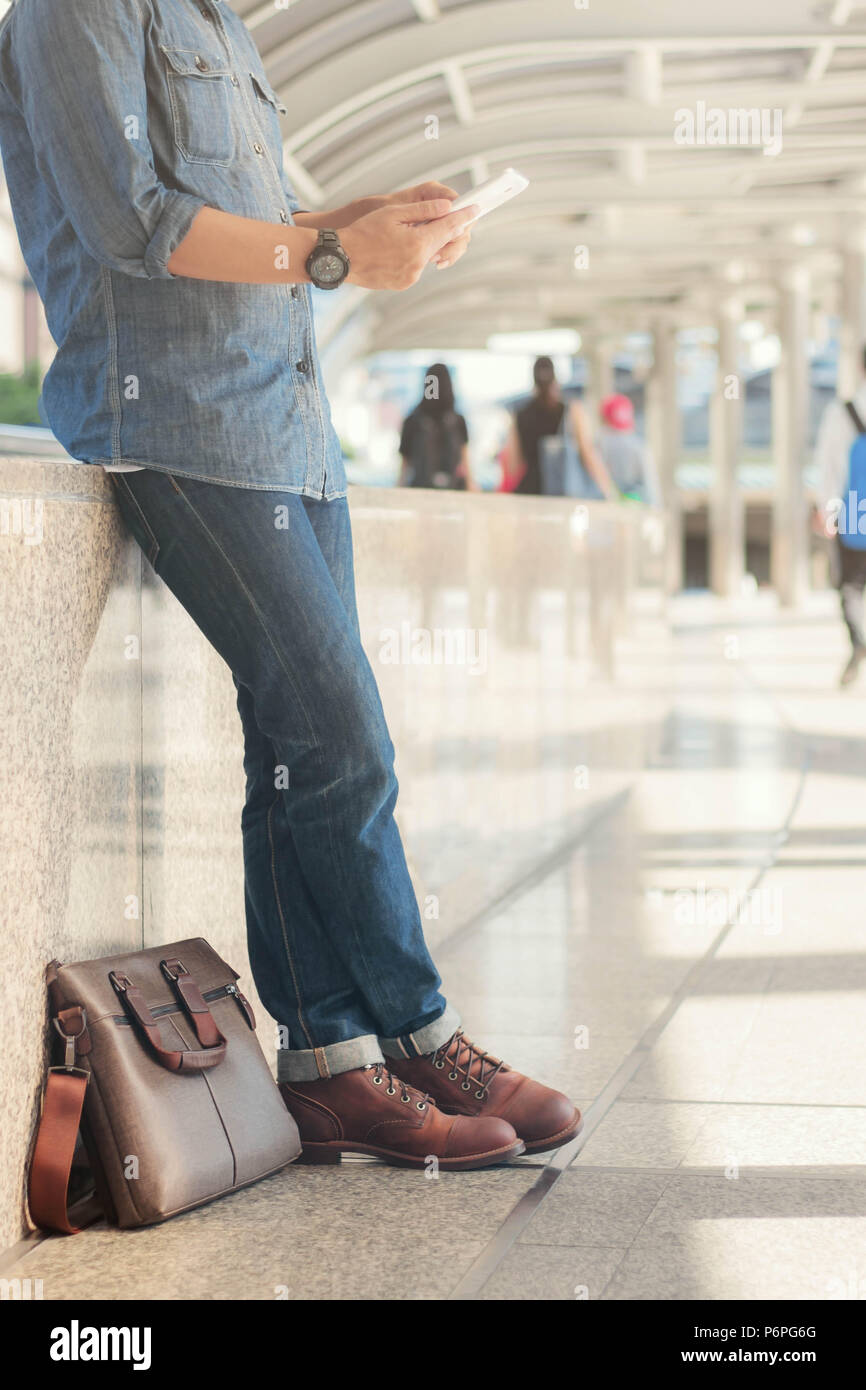 Men with blue jeans standing using smart phones Stock Photo - Alamy