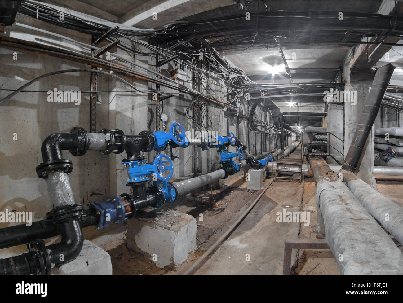 Blue valves on the water pipelines in an underground utility tunnel ...