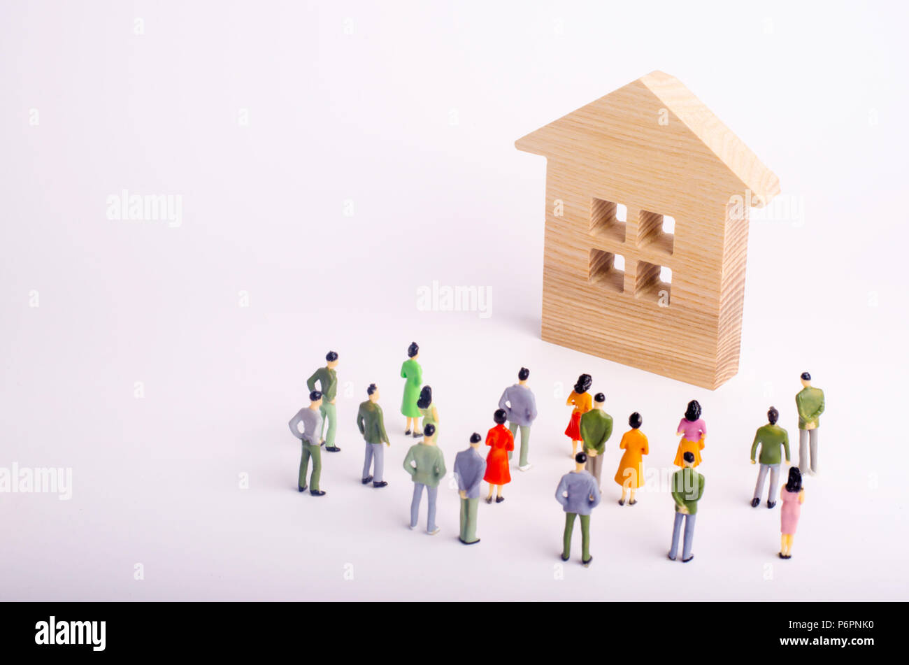 A crowd of people standing and looking at a wooden house on a white ...