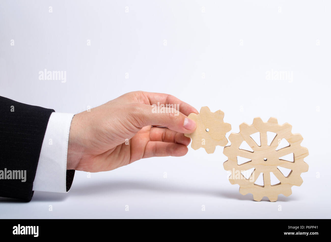hand of businessman in suit holds the gear to another gear wheel. The ...