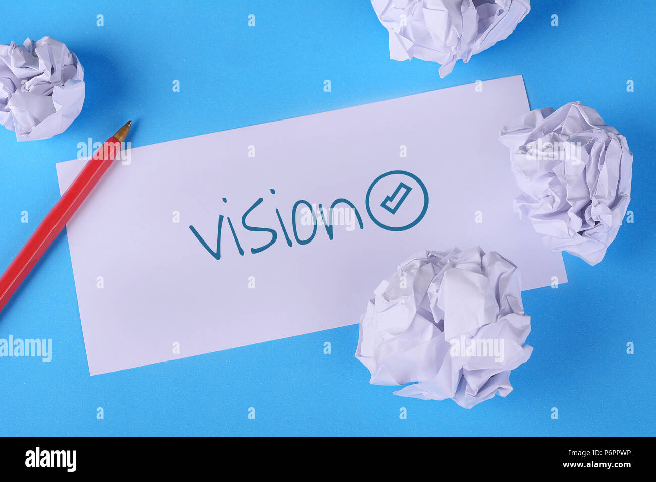 Paper with "vision" text and crumpled paper balls on light blue ...