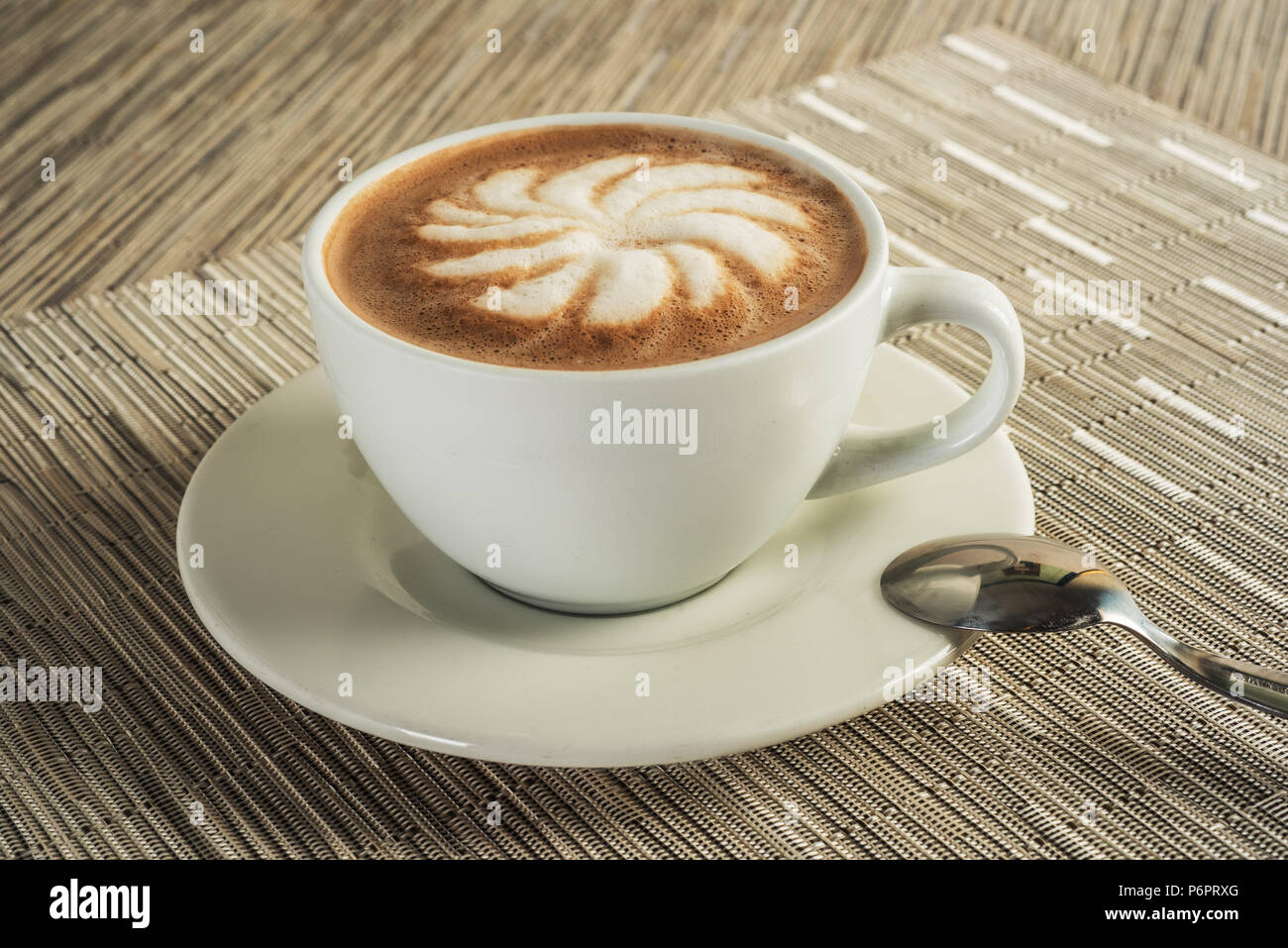 Spiral cappuccino coffee with wooden background, with a metal teaspoon ...