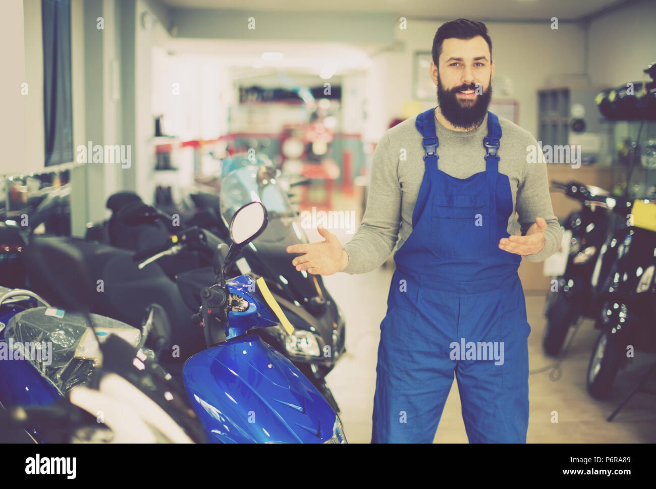 Male worker demonstrates different models of motorcycles in his ...