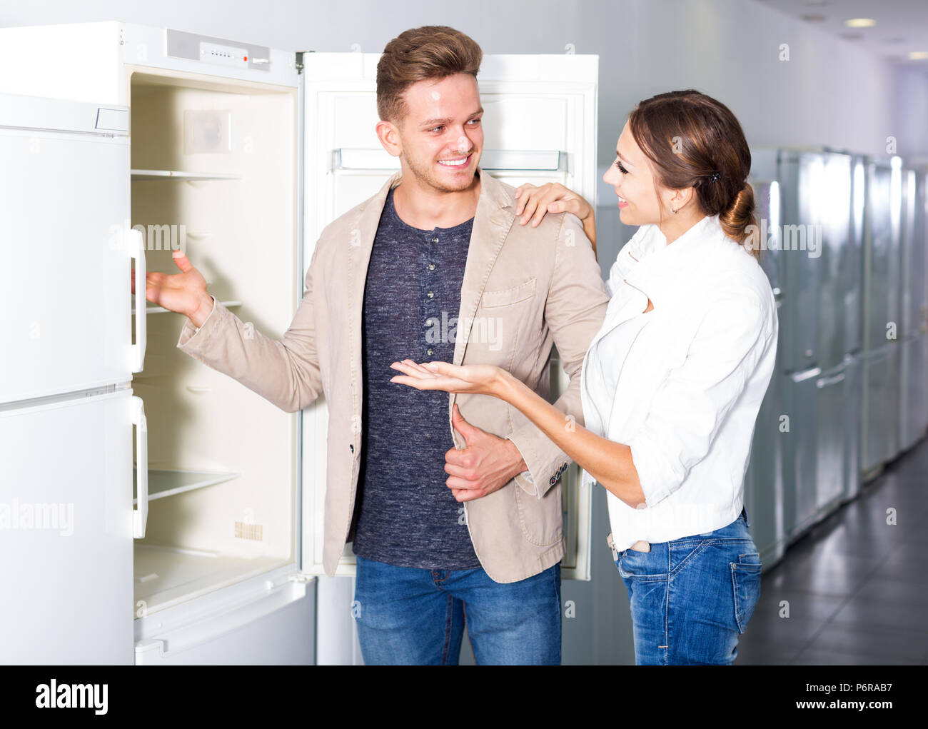 Smiling middle class family couple choosing new refrigerator in ...