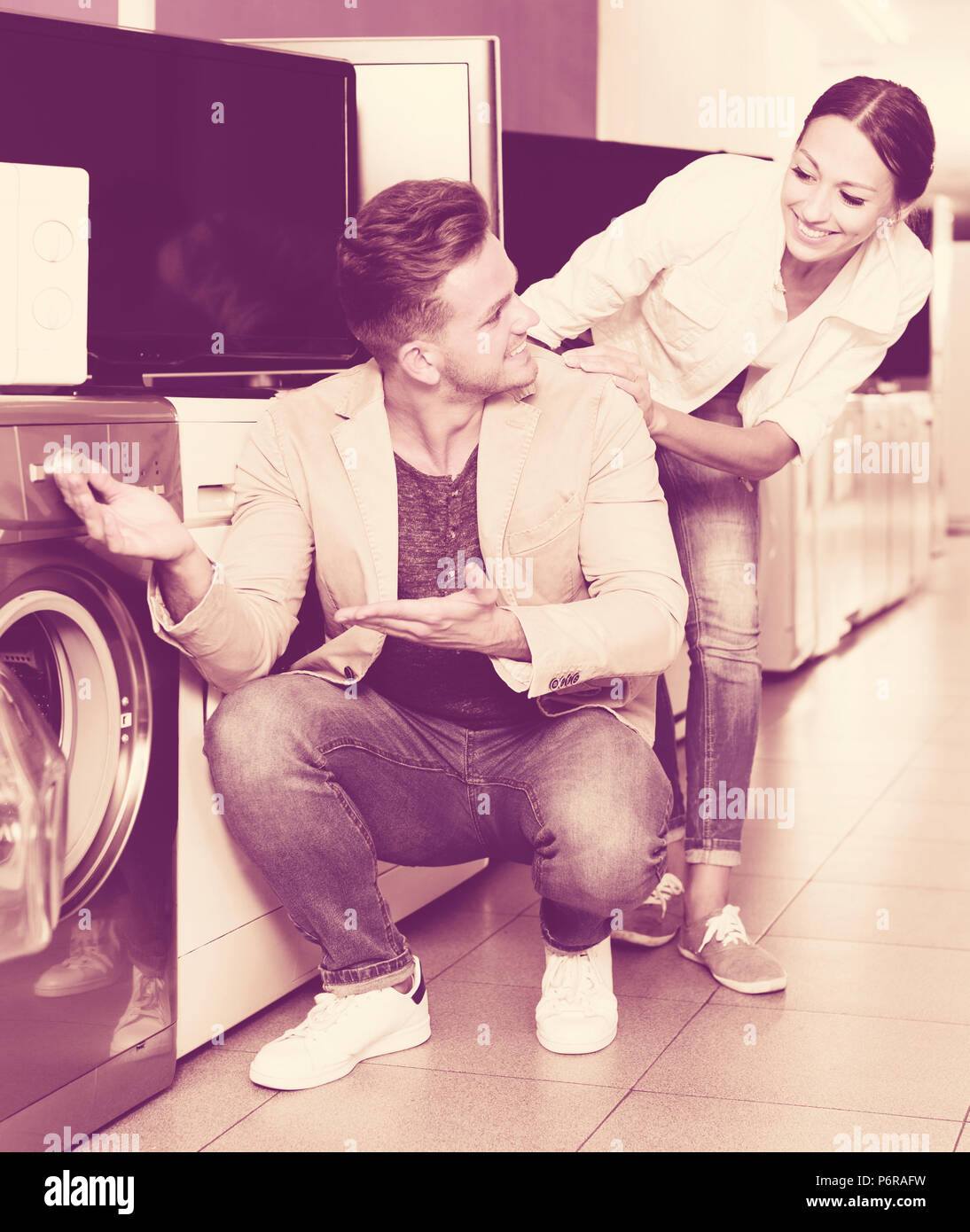 Family couple looking at laundry machine in domestic appliances section ...
