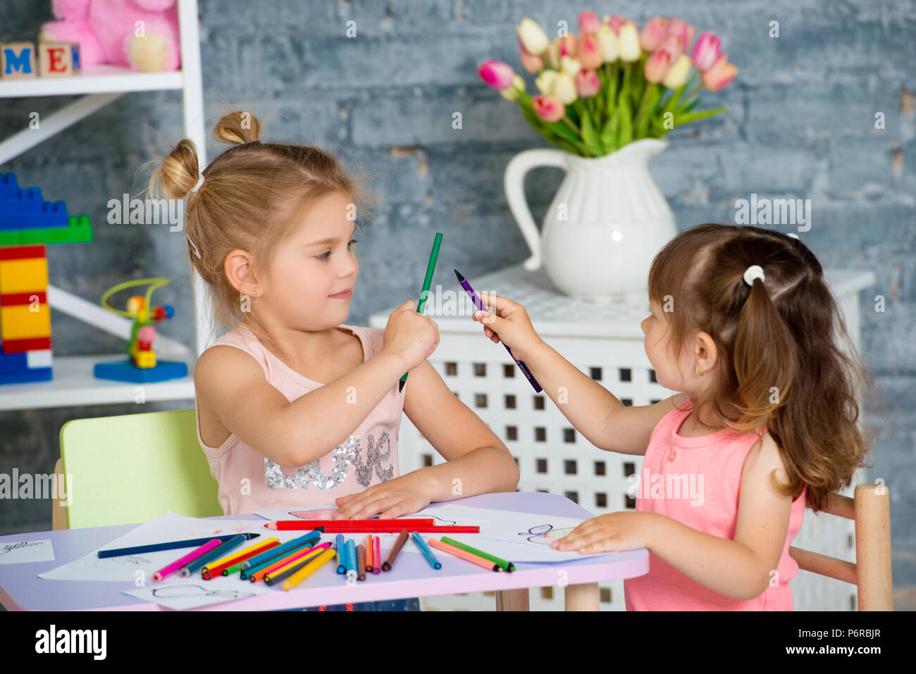 Two little beautiful girls draw with colorful pencils Stock Photo - Alamy