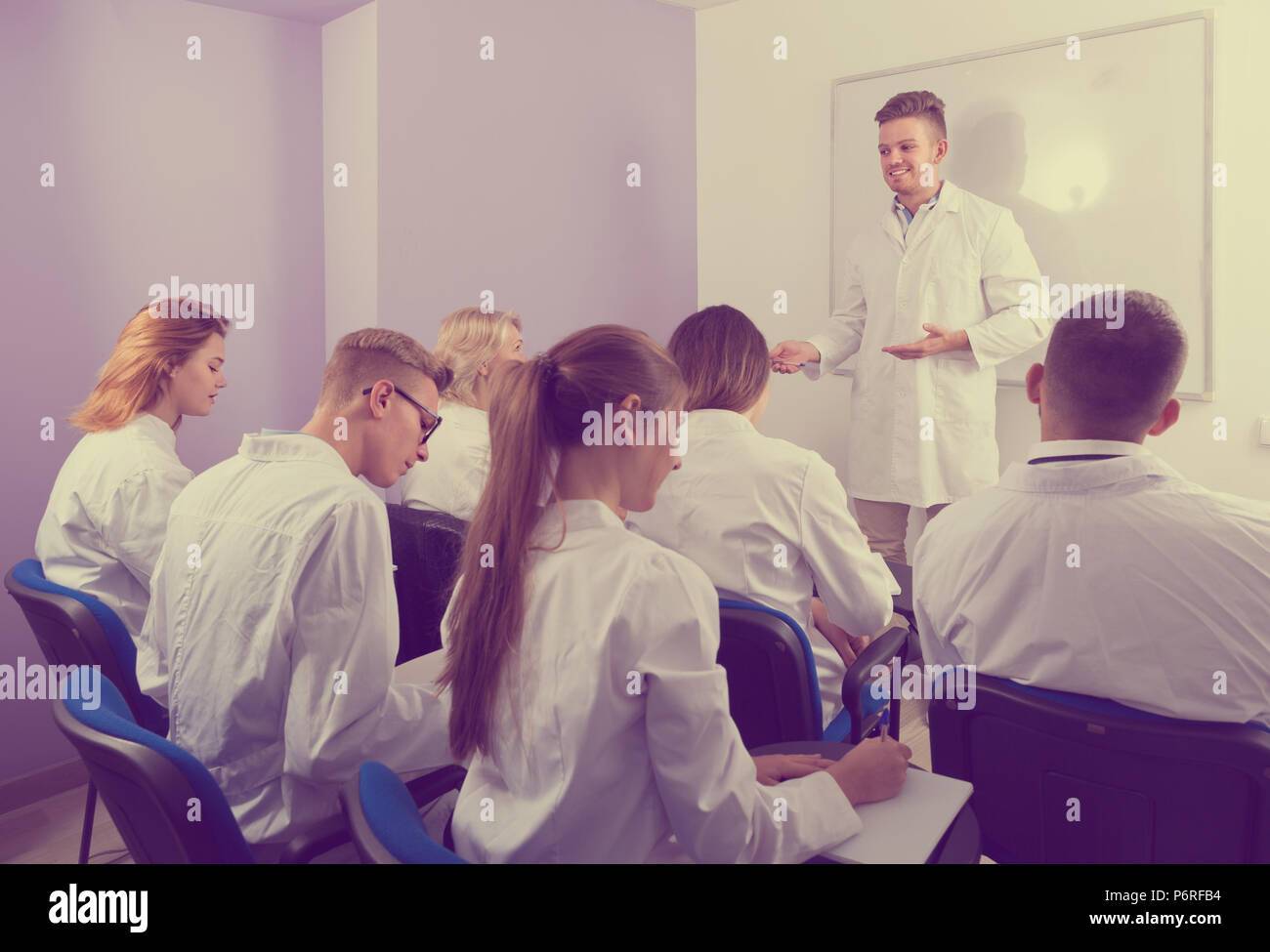 Adult male student answering near whiteboard in front of teacher and ...