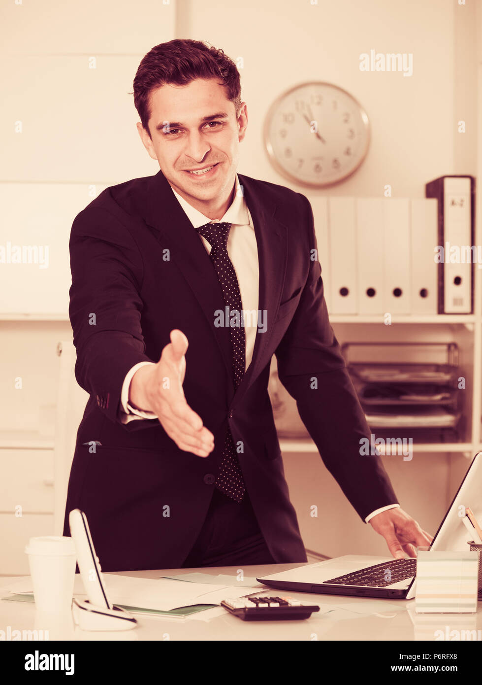 Successful businessman standing in office with open hand ready for ...
