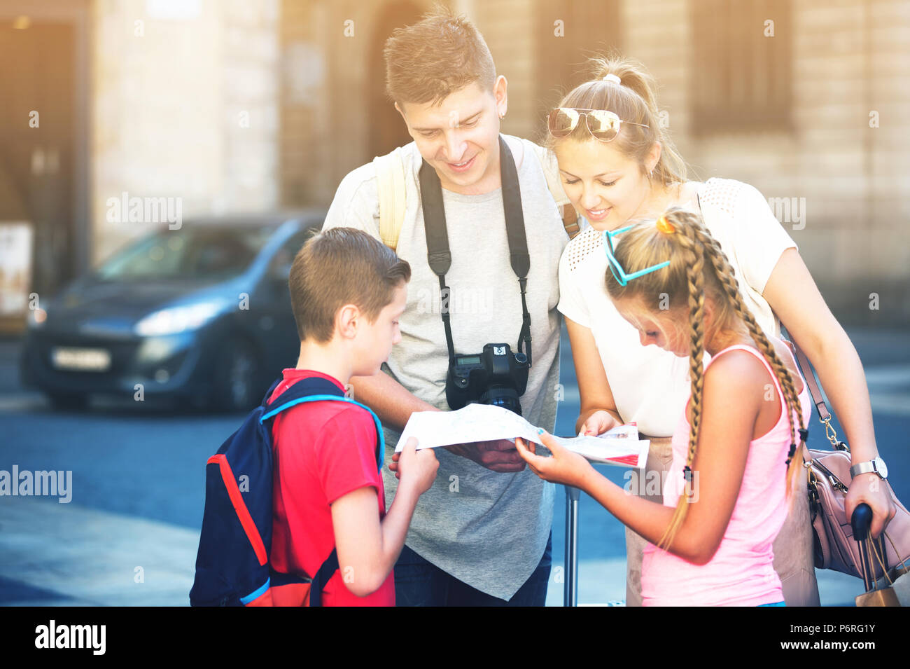 Young happy family of tourists with two kids looking for destination ...