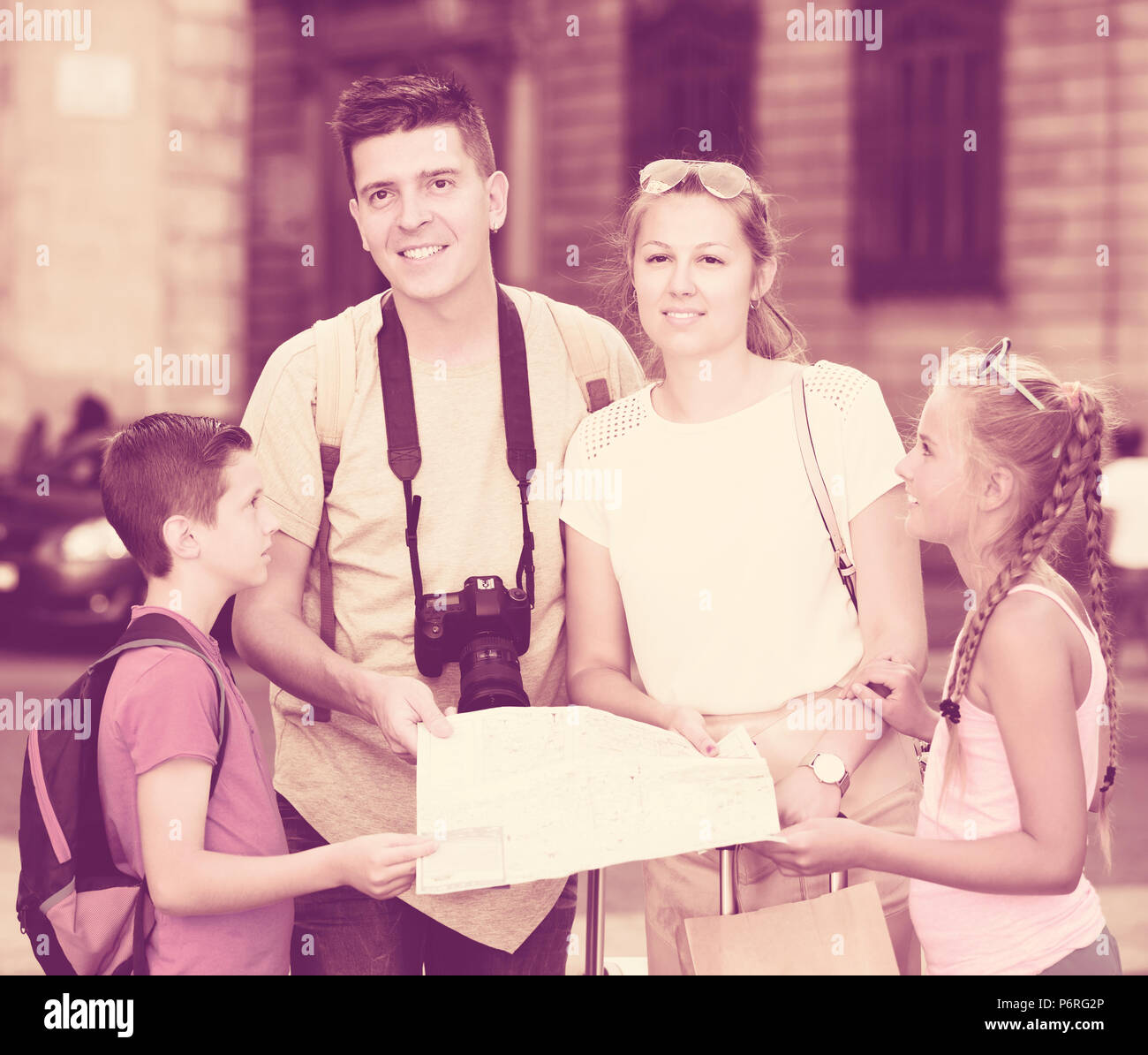 Young cheerful family of tourists with two kids looking for destination ...