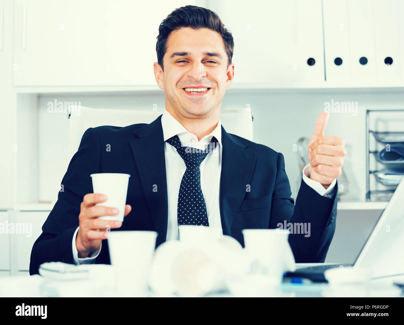 Relaxed businessman giving thumbs as sign of successful finish of work ...