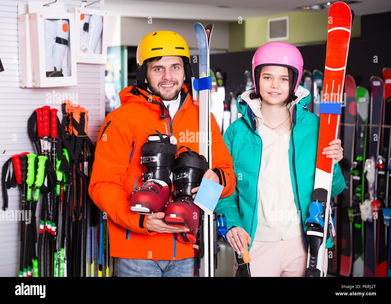 Portrait of cheerful customers posing in full skiing gear during ...
