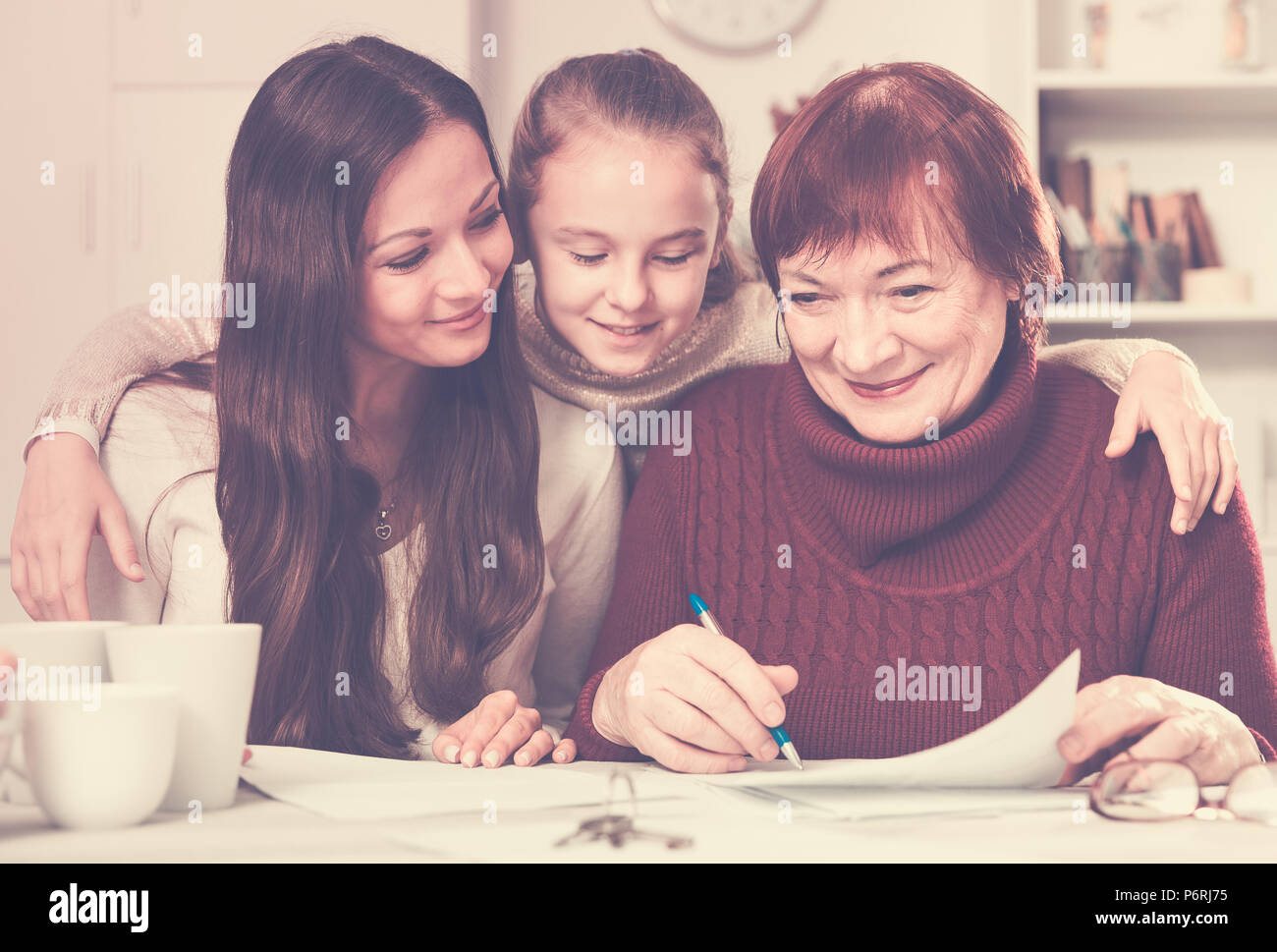 Three generations of happy family working together with documents at ...