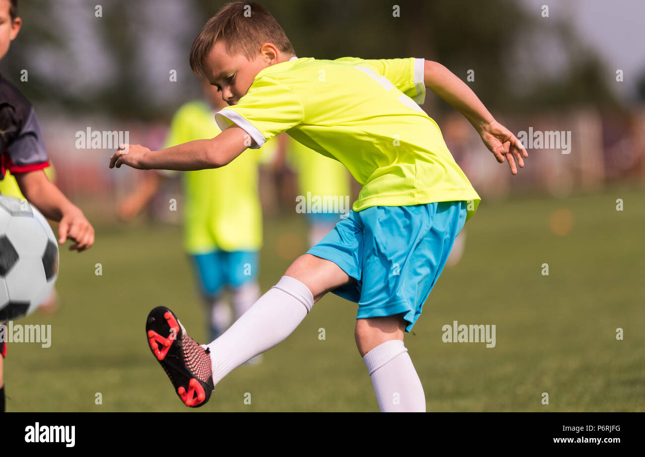 Boy kicking football on the sports field during soccer match Stock ...