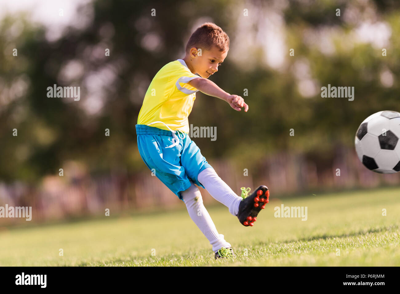 Boy kicking football on the sports field during soccer match Stock ...