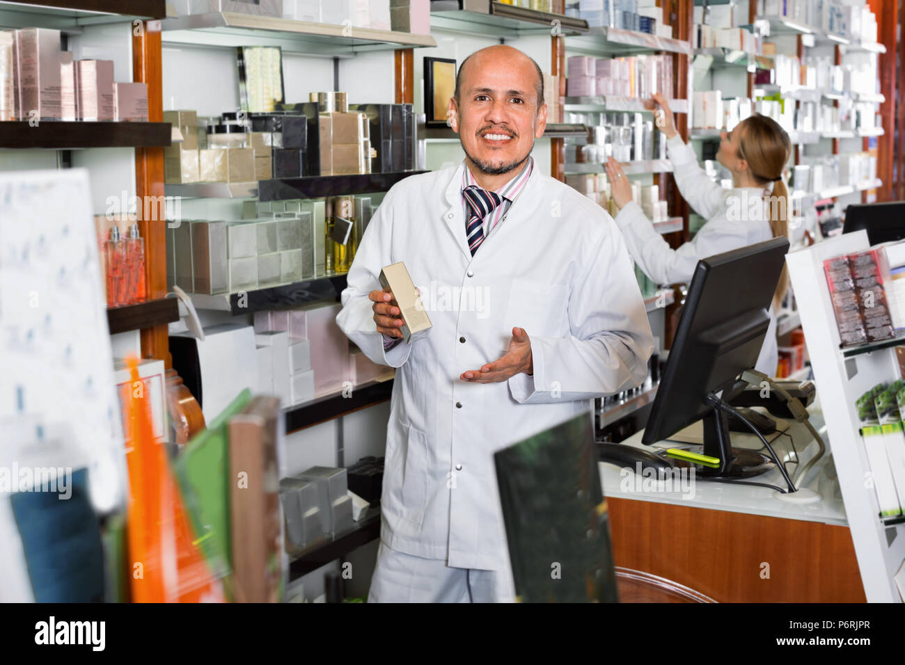 Two smiling female and male pharmacists in white coats working the ...