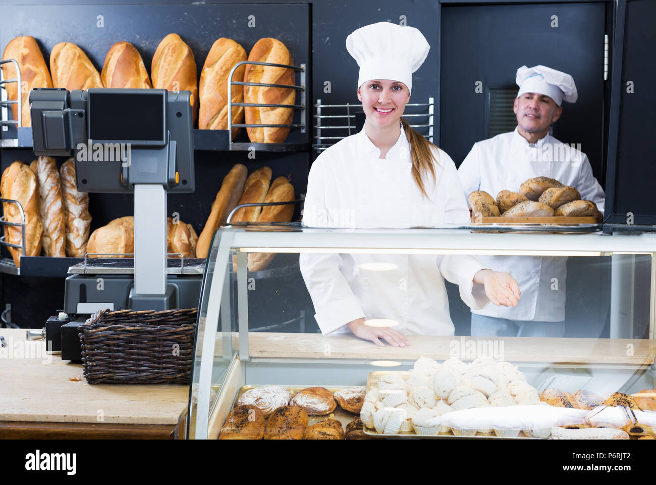 Portrait of smiling man and women bakery employees offering delicious ...