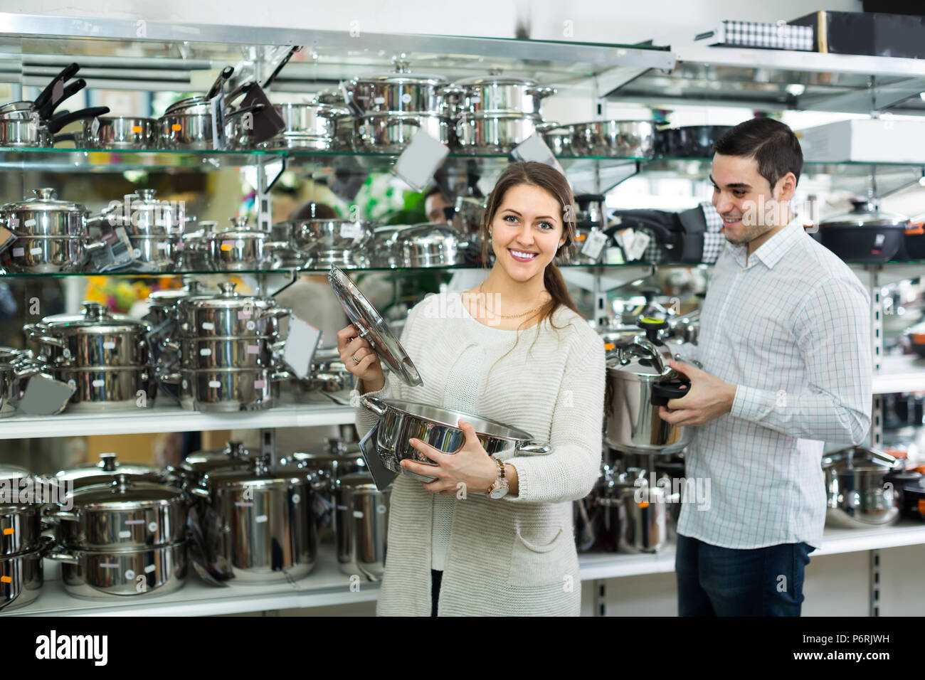 Happy young family choosing new pans in kitchenware section in ...