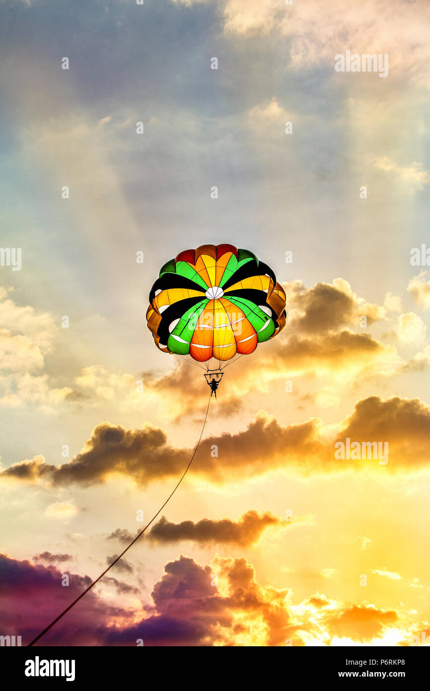 Recreational parasailing with a canopy wing against a colourful sky at ...