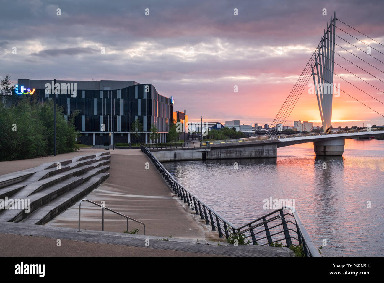 Colourful setting sun over water and Calatrava-style bridge in an urban ...