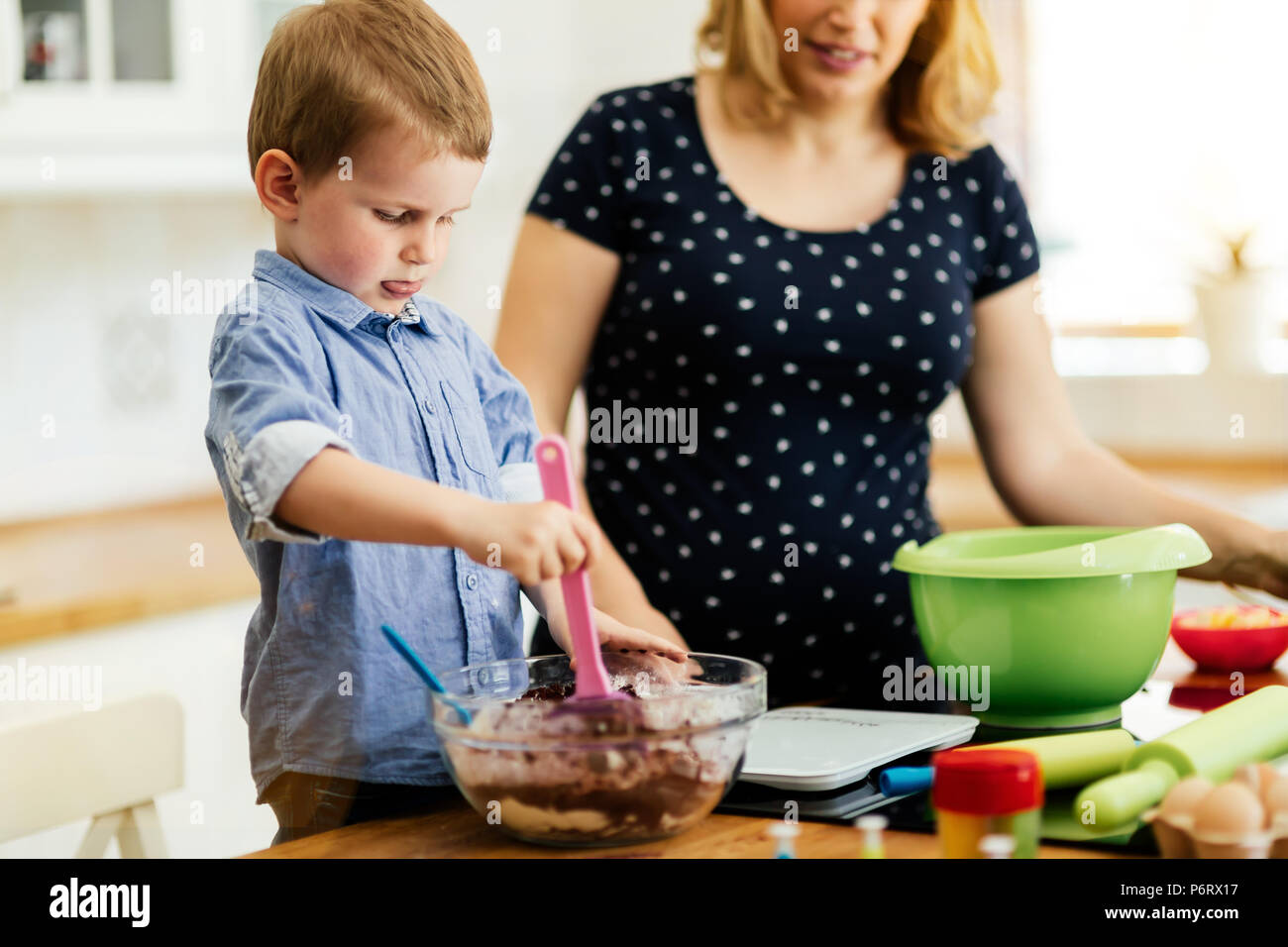 Smart cute child helping mother in kitchen Stock Photo - Alamy