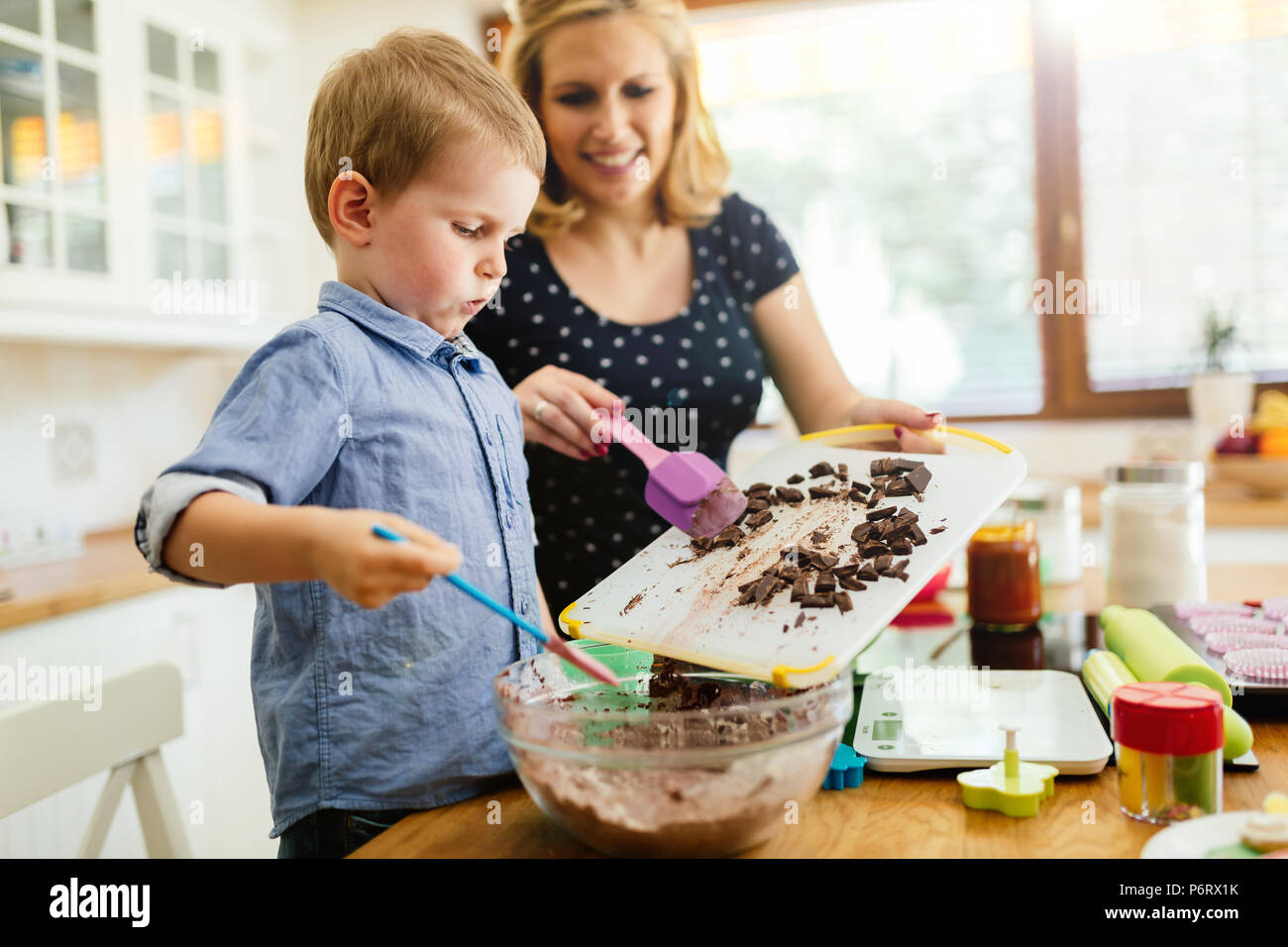 Smart cute child helping mother in kitchen Stock Photo - Alamy