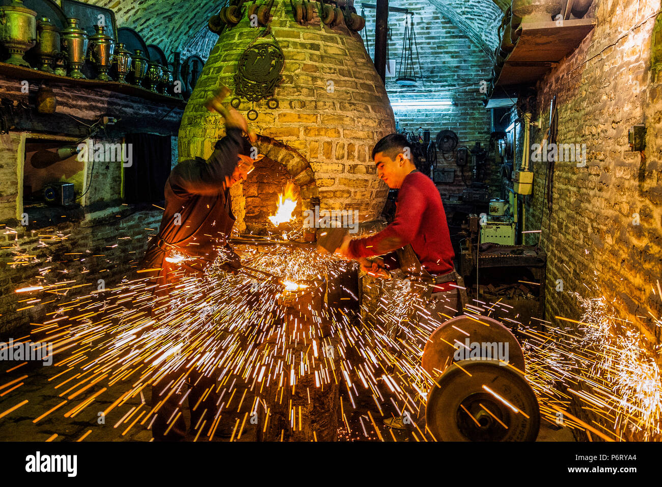 A blacksmith hammers on the glowing iron with a hammer and creates ...