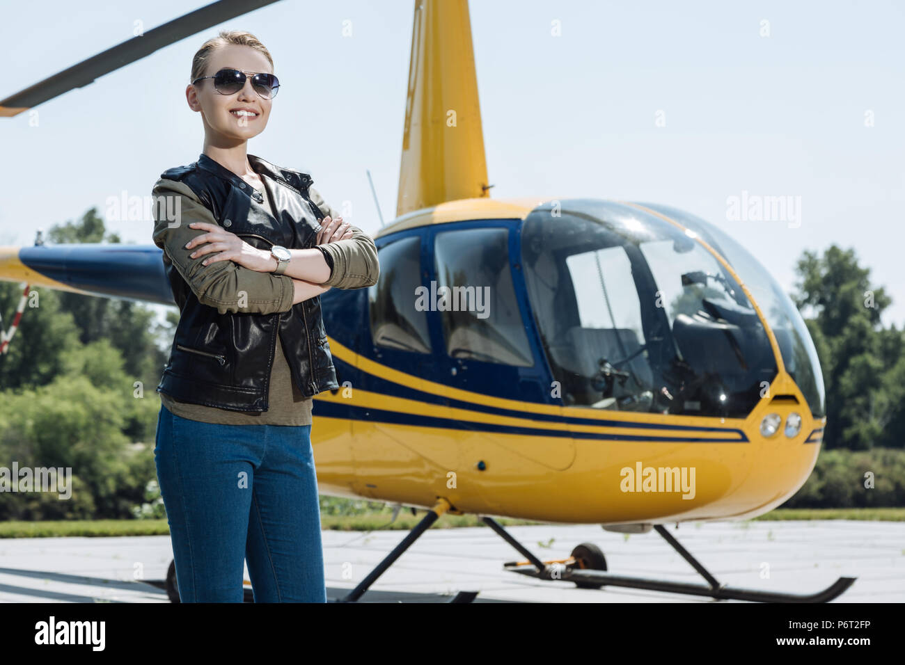 Pretty female pilot posing near helicopter Stock Photo - Alamy