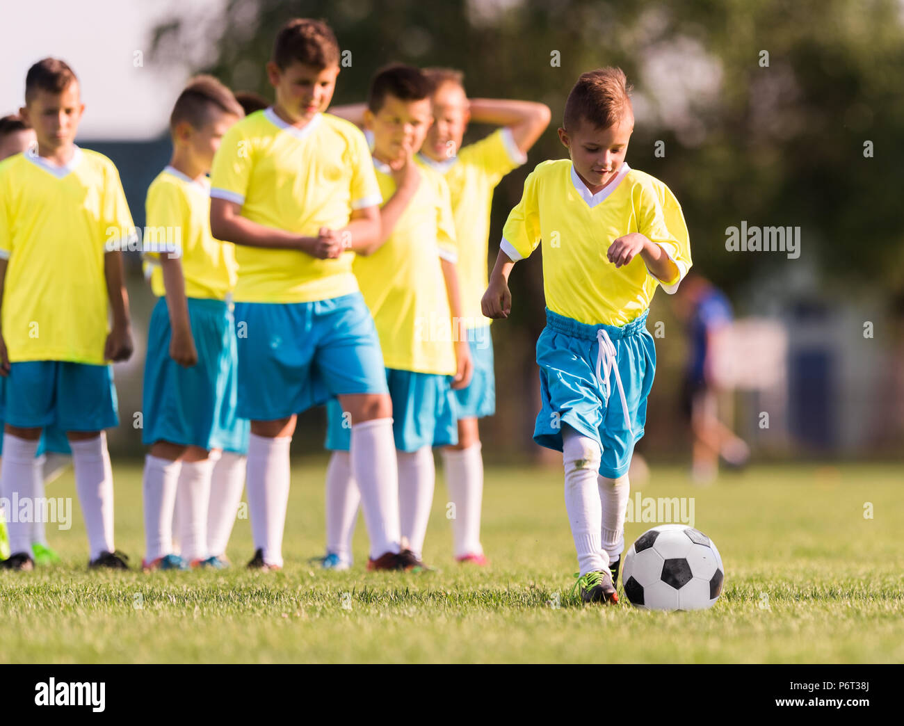 Boy kicking football on the sports field during soccer match Stock ...