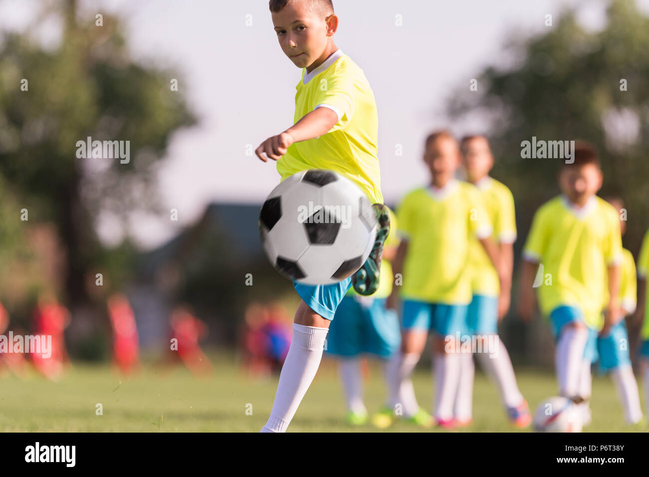 Boy kicking football on the sports field during soccer match Stock ...
